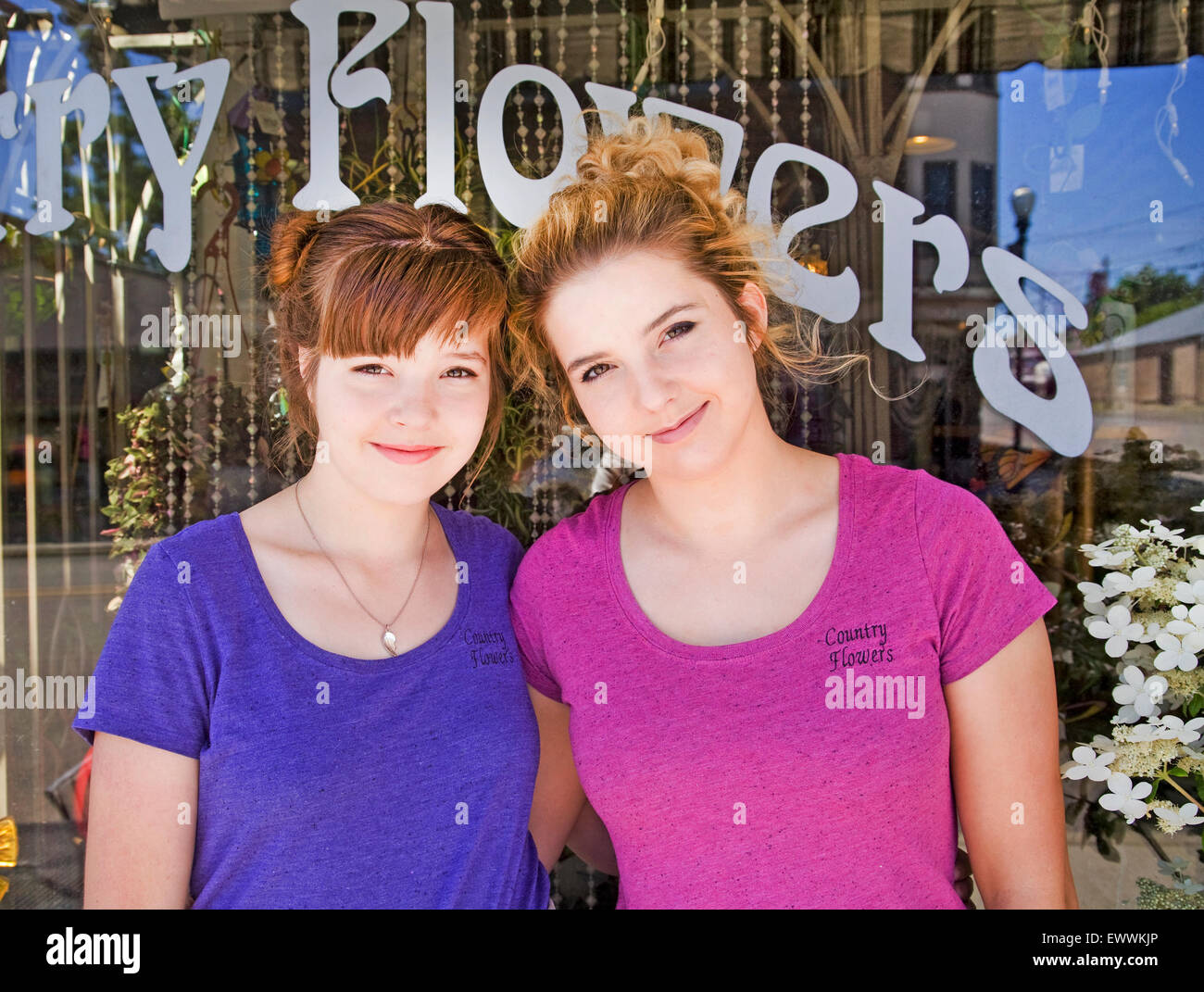 Two pretty teen-aged girls, who are sisters, stand in front of their ...