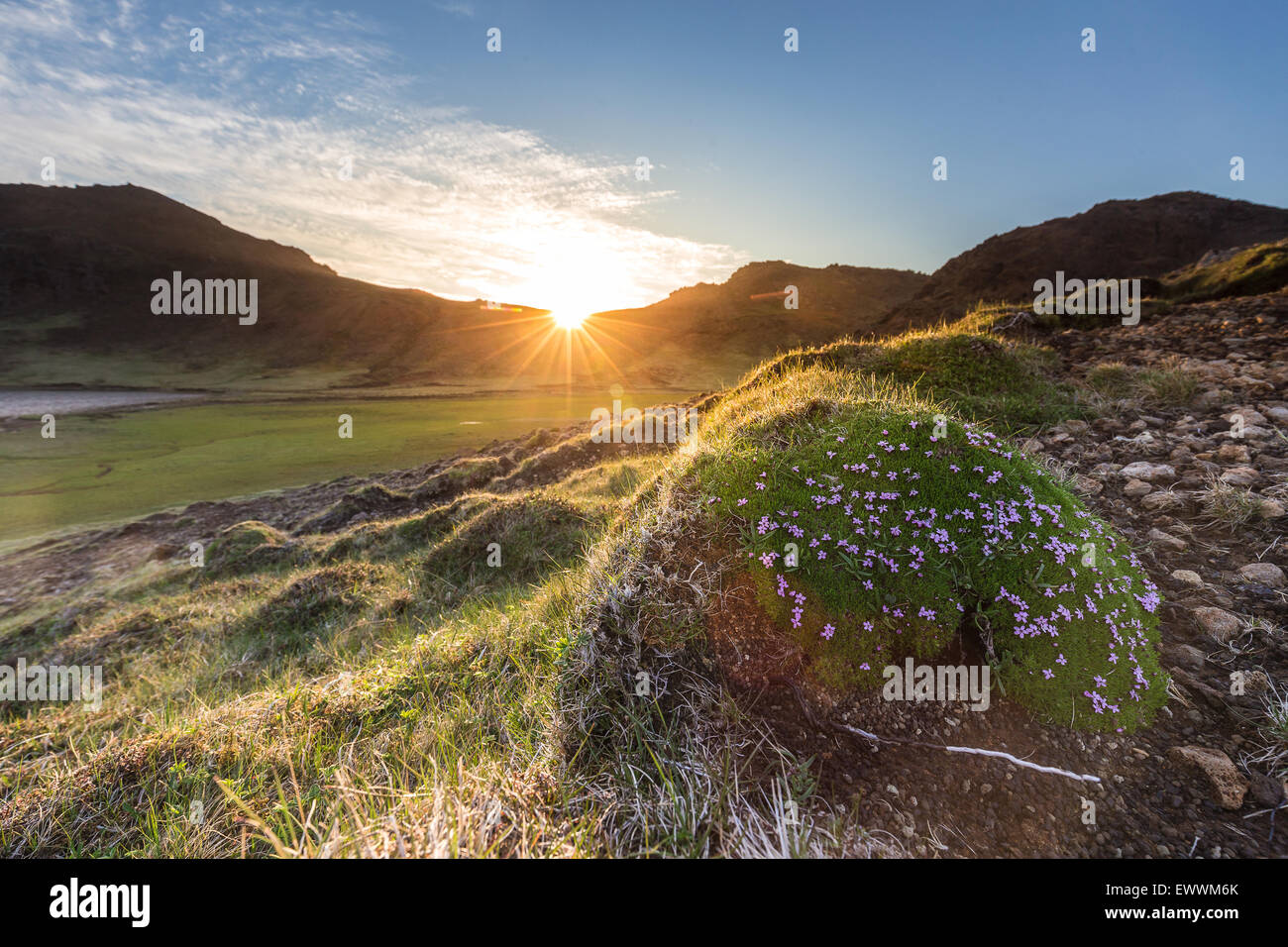 Sun setting behind mountains lighting up some fields and meadows in ...