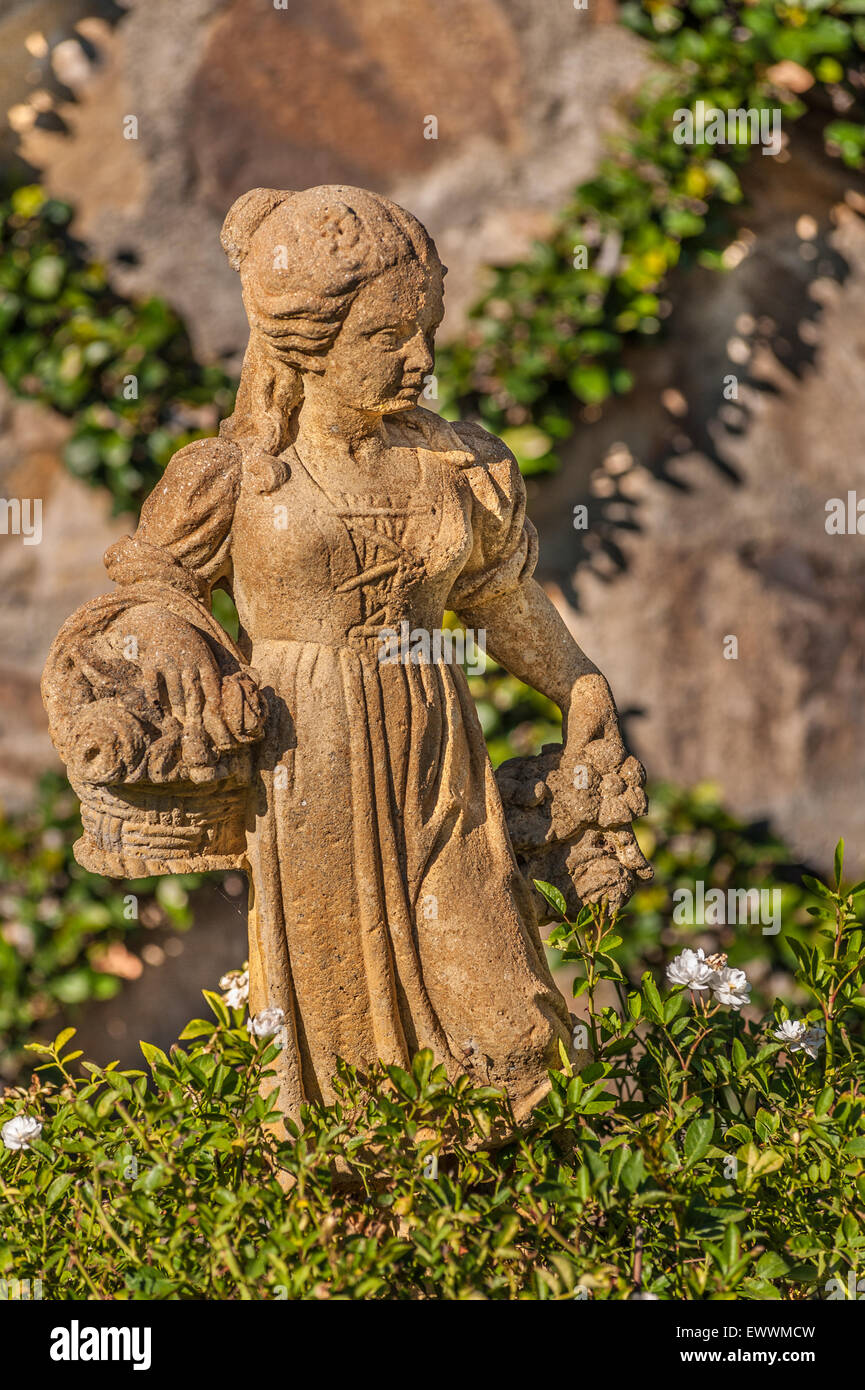 Stone garden statue of girl with flower basket, stone backdrop Stock ...