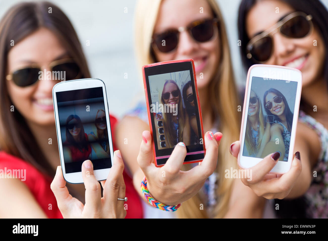 Portrait of three friends taking photos with a smartphone Stock Photo ...