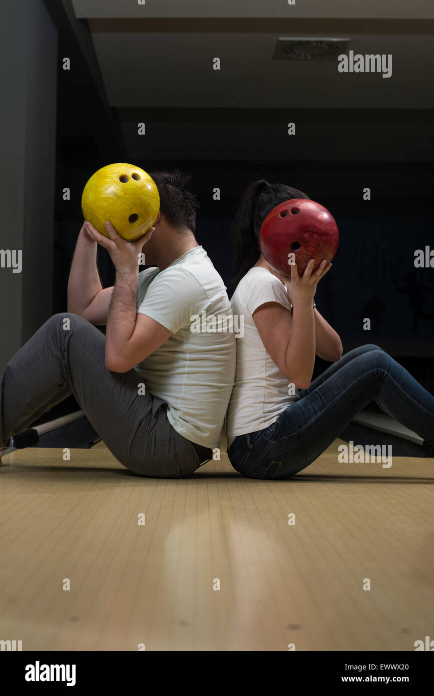 Young Couple Hiding Their Faces Behind Bowling Ball Stock Photo - Alamy