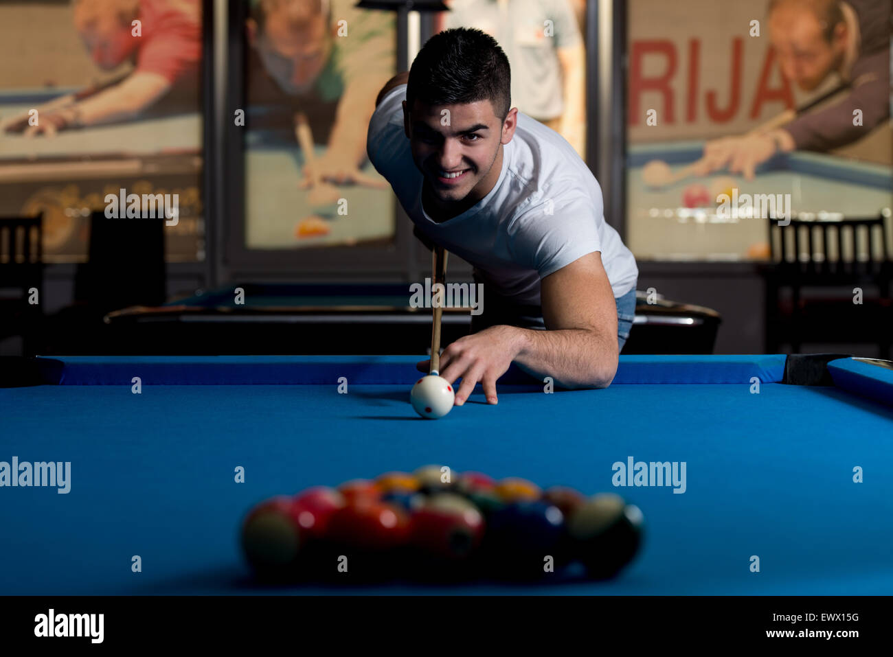 Young Man Lining To Hit Ball On Pool Table Stock Photo - Alamy