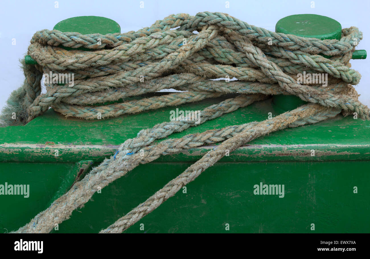 Tied mooring ropes on a green metal harbor bollard in the harbor of ...