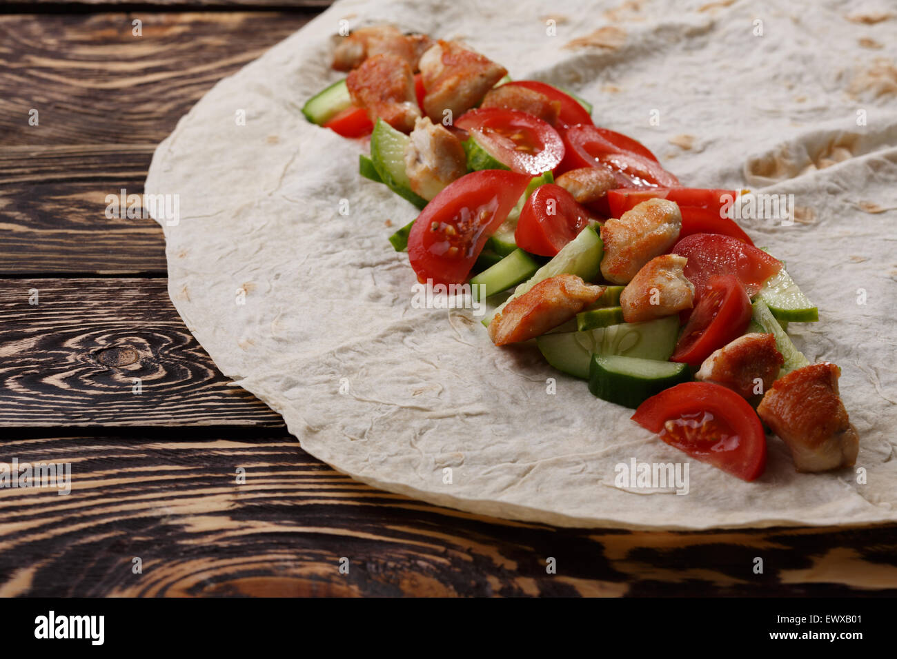Traditional shawarma wrap with chicken and vegetables on wooden table ...