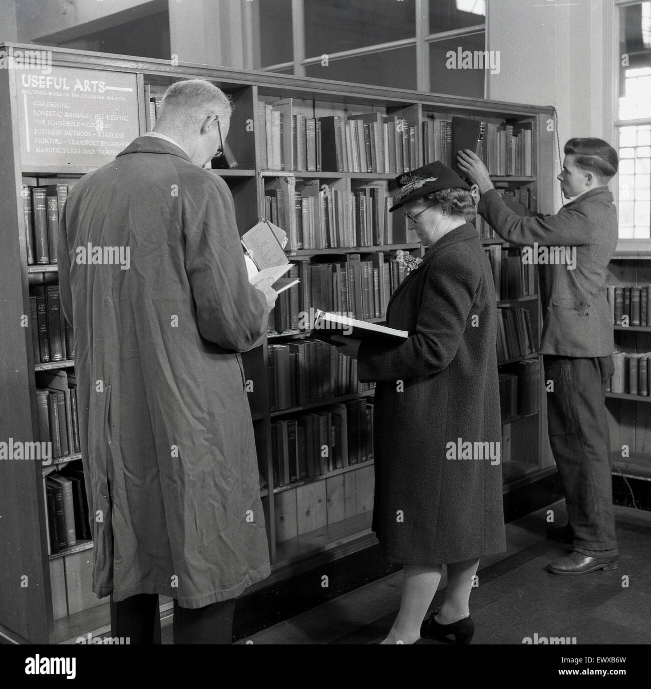 Historical, 1950s, picture shows people looking at books in a library ...