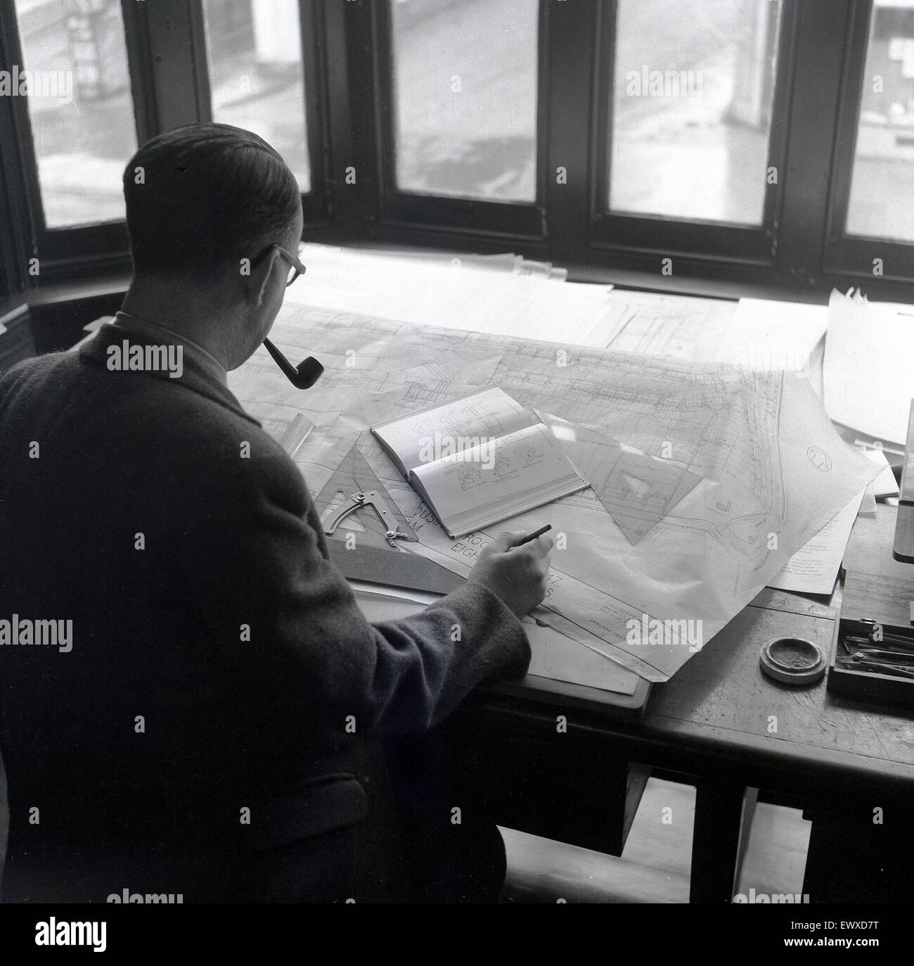 Historical, 1950s, picture shows an architect at desk smoking a pipe ...