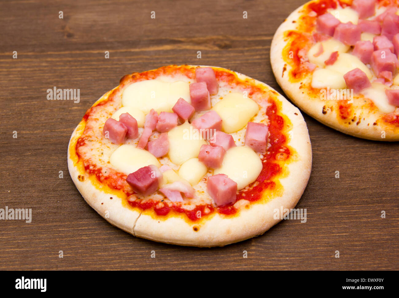 Mini pizzas with ham on wooden table Stock Photo - Alamy