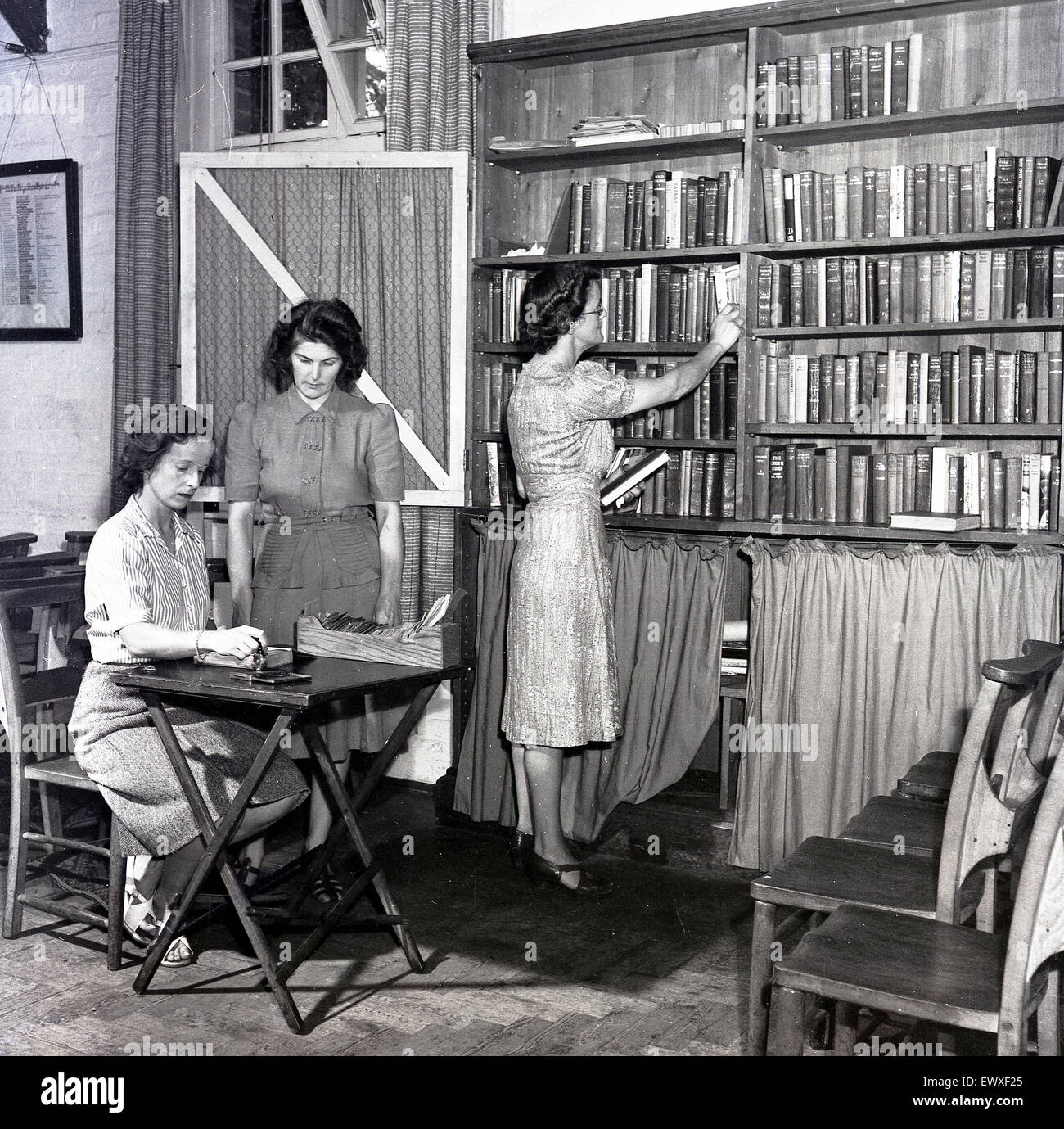 Historical, 1950s, picture shows three ladies helping arrange the ...