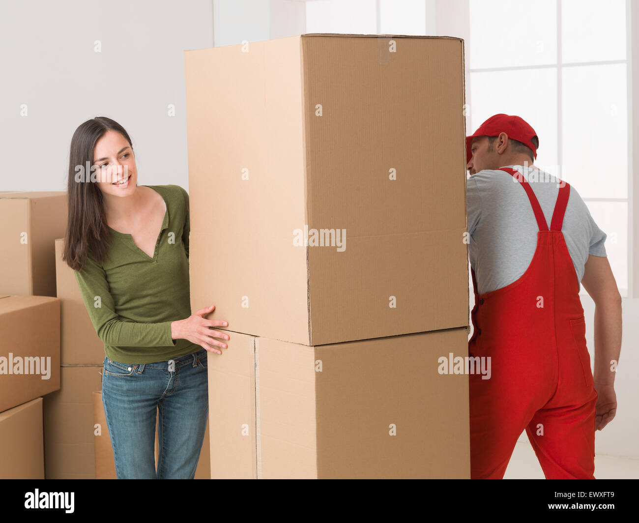 young woman and deliveryman playing hide and seek around cardboard ...