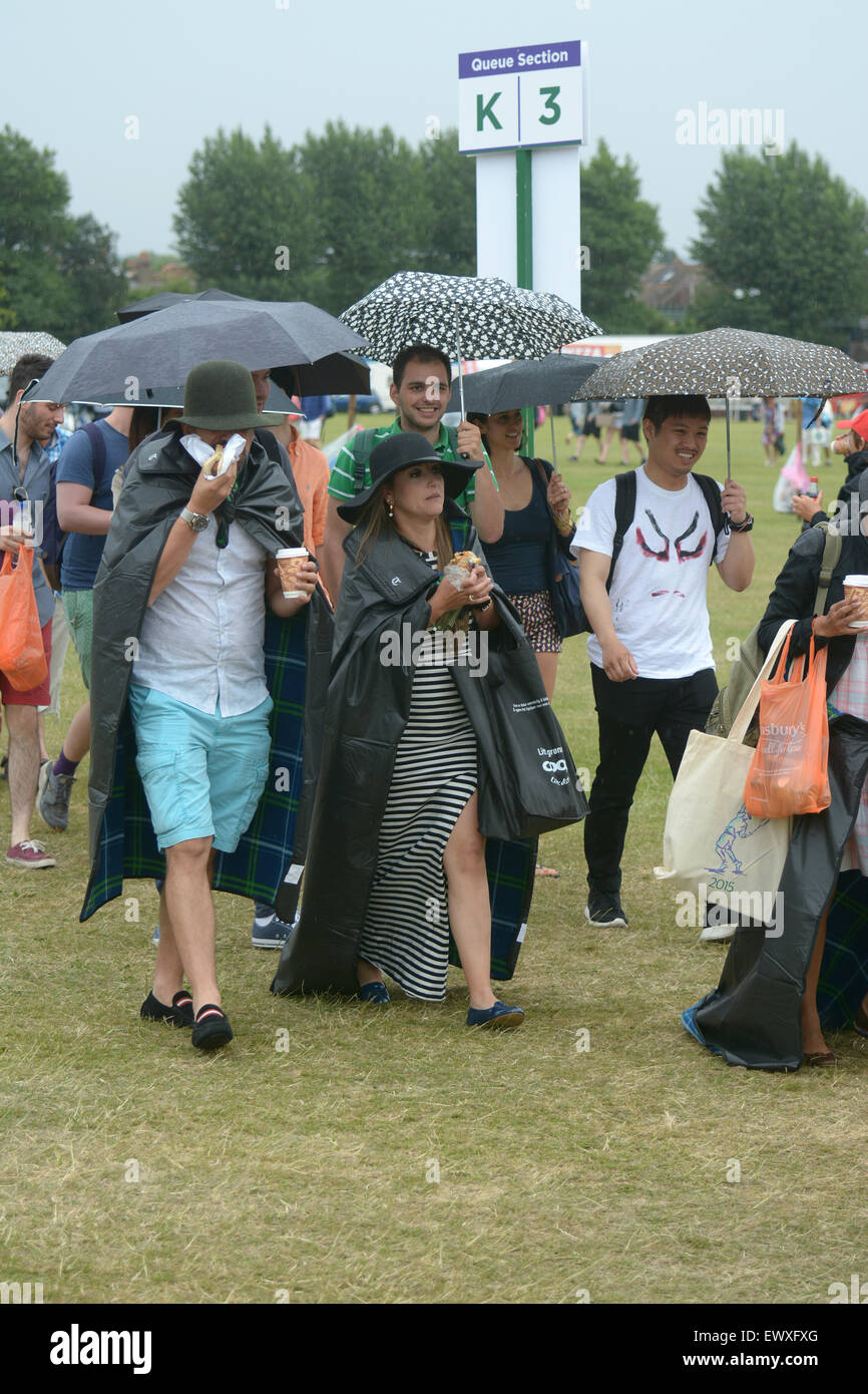 A group of people shelter under umbrellas as they queue in the rain for ...