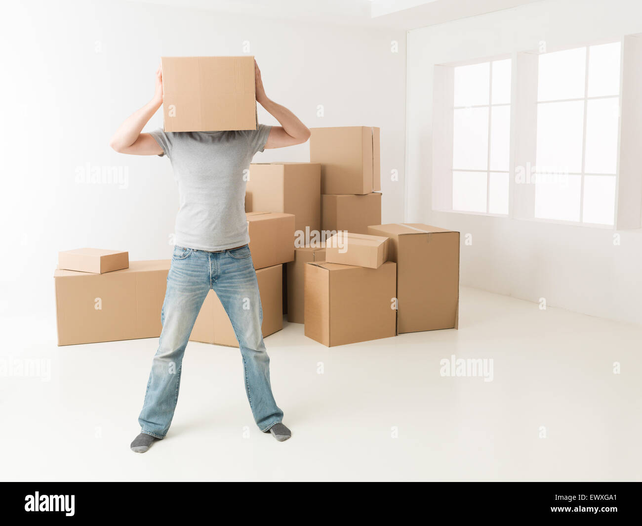 man hiding his head in cardboard box, standing in new apartment ...