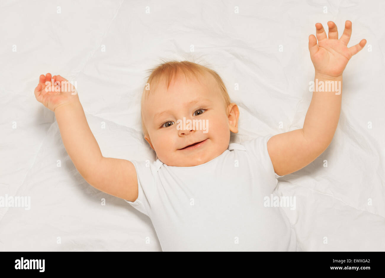 Chubby small baby with arms up on white blanket Stock Photo - Alamy