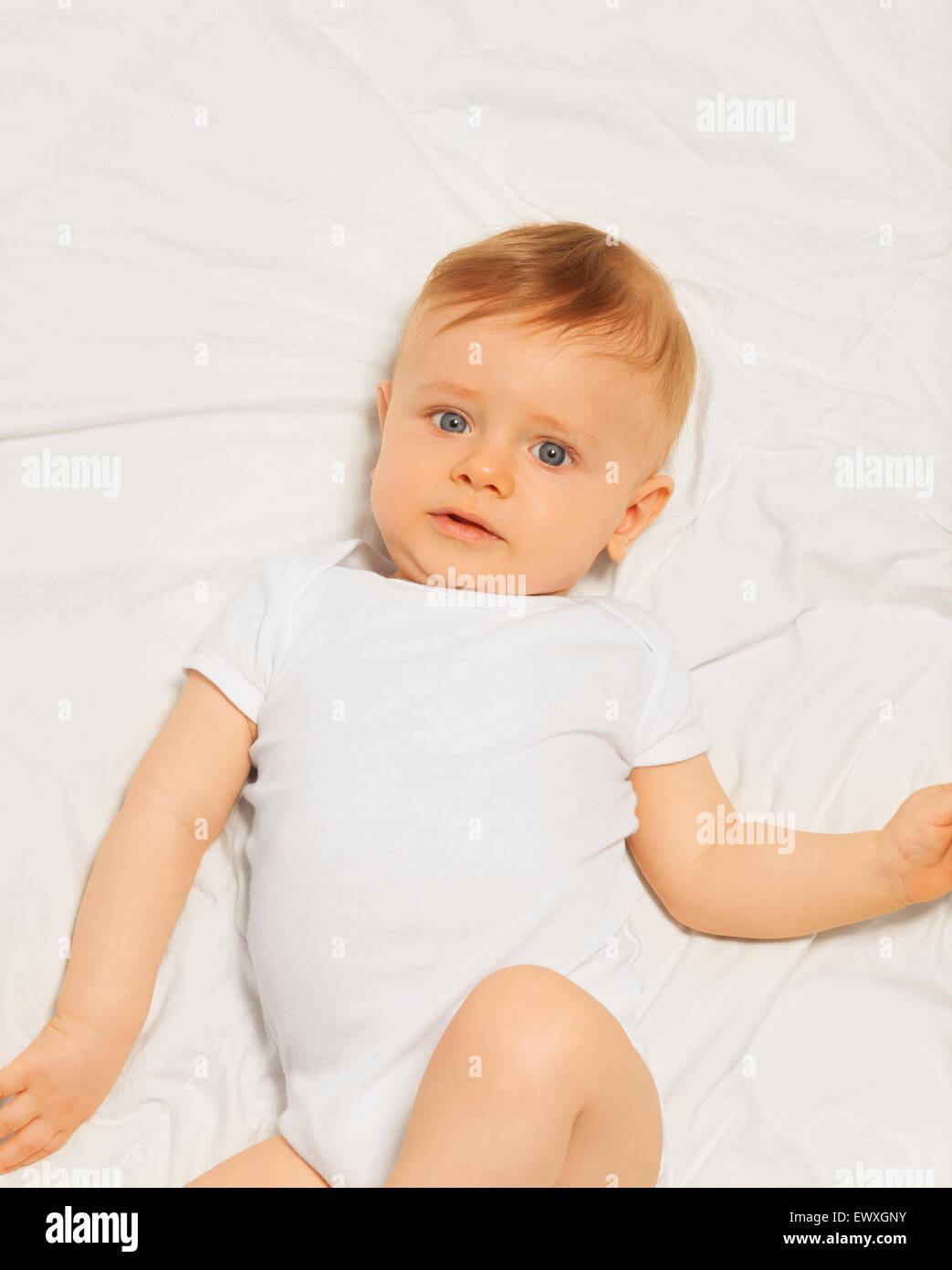 Chubby sad small baby wearing white bodysuit lay Stock Photo - Alamy