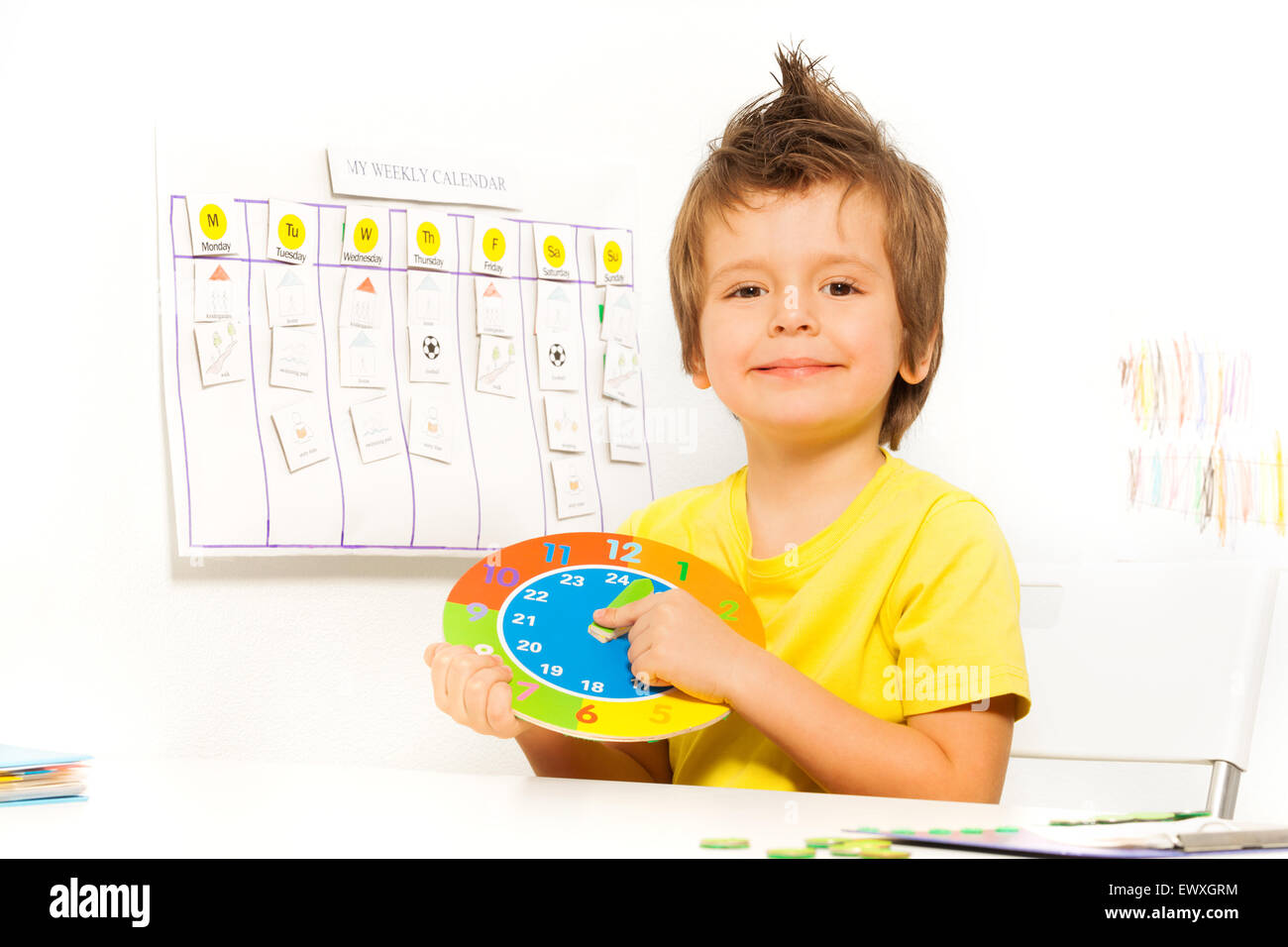 Smiling boy holding colorful carton clock sitting Stock Photo - Alamy