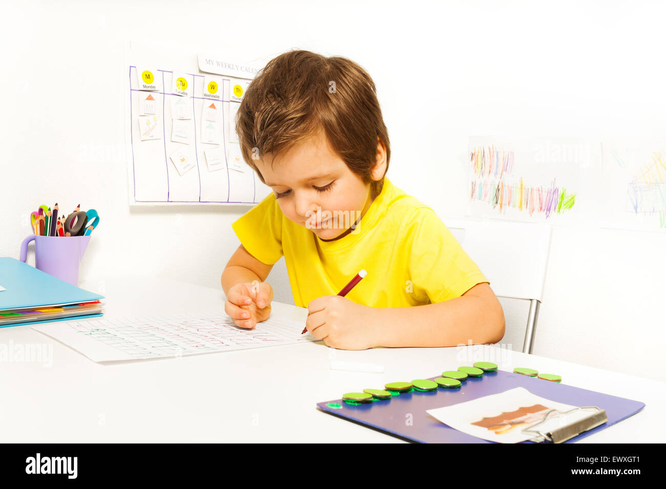 Concentrated small boy write with pencil alone Stock Photo - Alamy