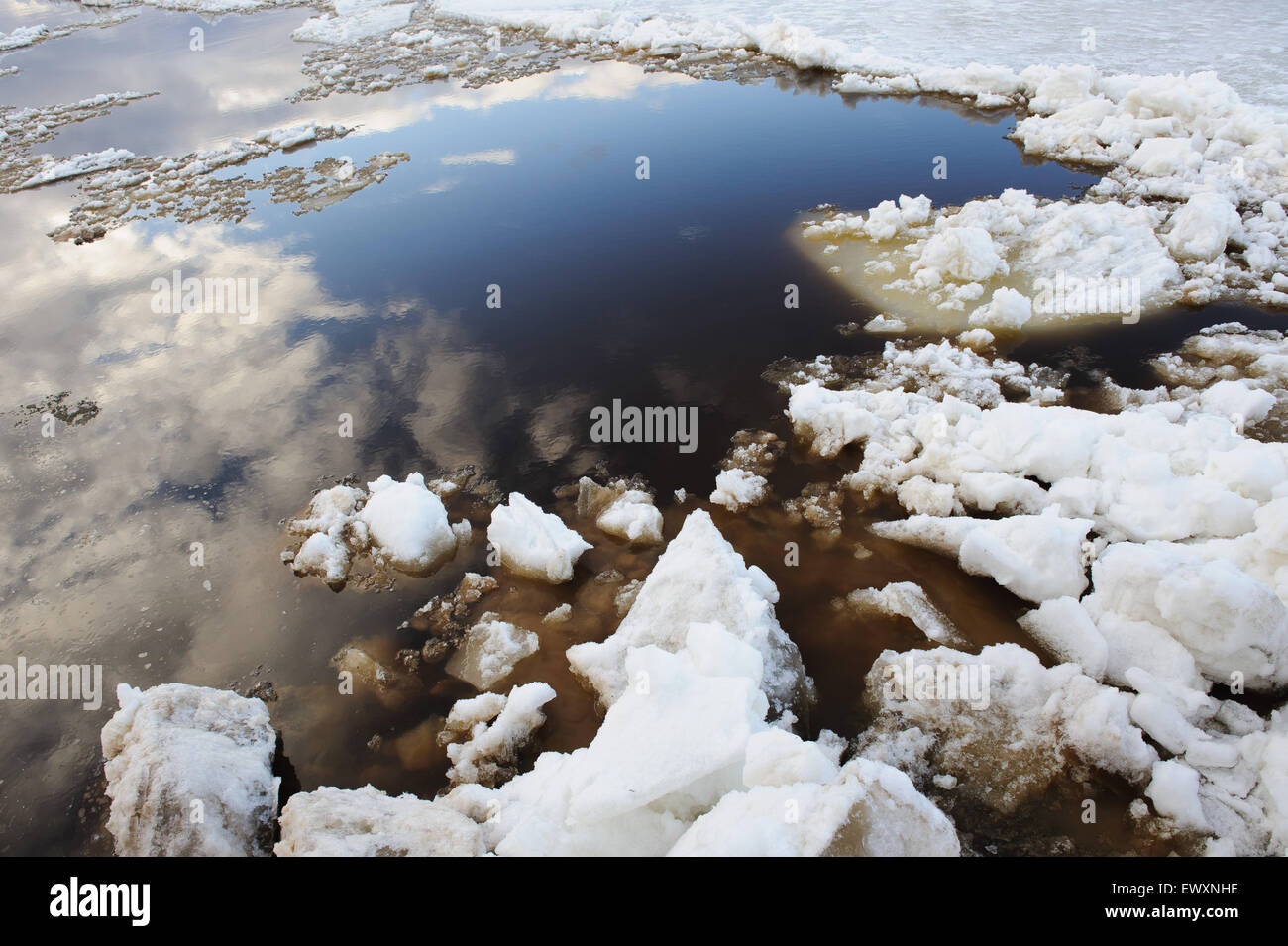 Thawing of ice with reflection of sky in water Stock Photo - Alamy