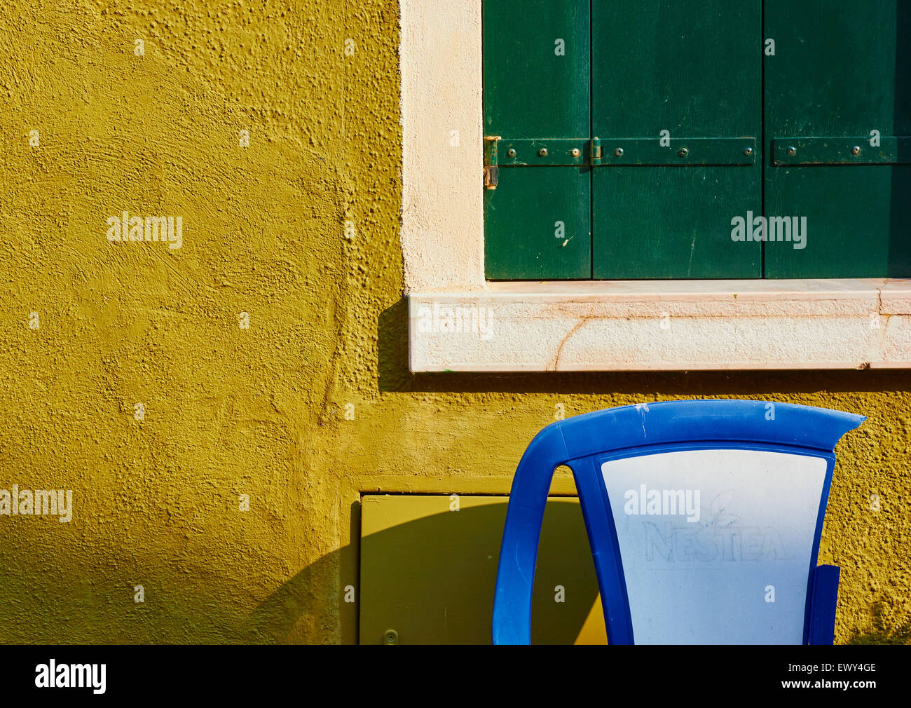 Blue and white broken plastic chair outside a green painted house at ...