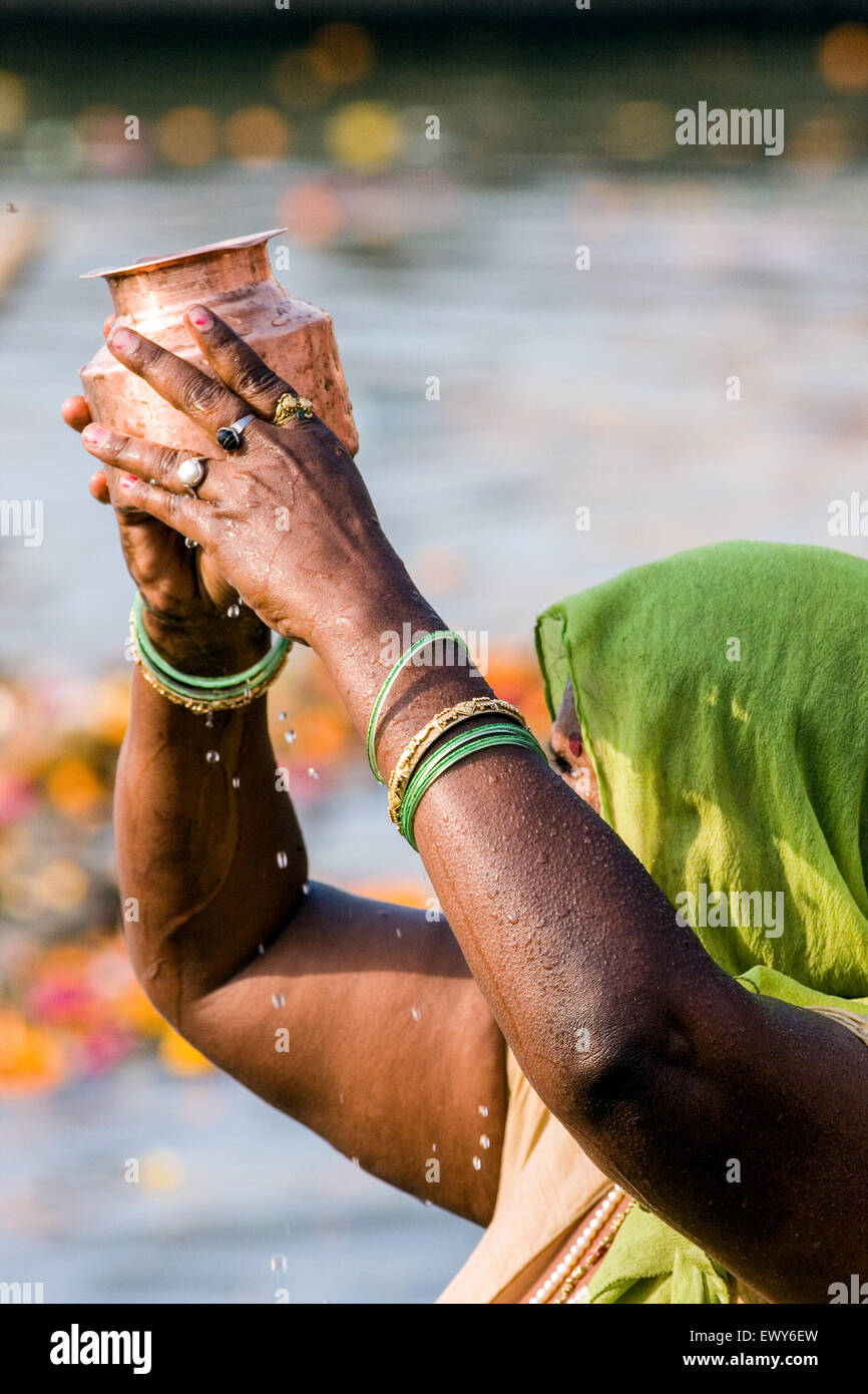 Hindu woman immersed in the holy, but polluted, Ganges water, raises a ...