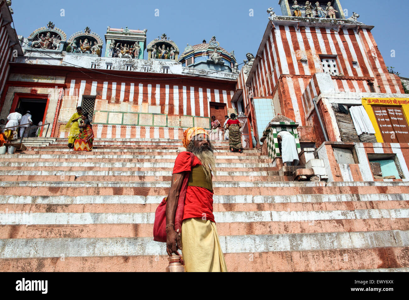 Hindu sadhu passing a Hindu temple and colourful stairs of the bathing ...