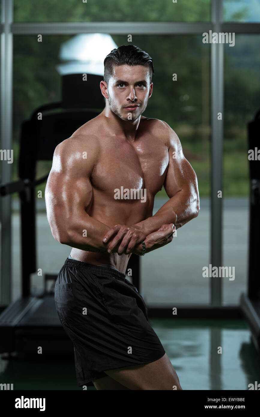 Serious Man Bodybuilder Standing In The Gym And Flexing Muscles Stock ...