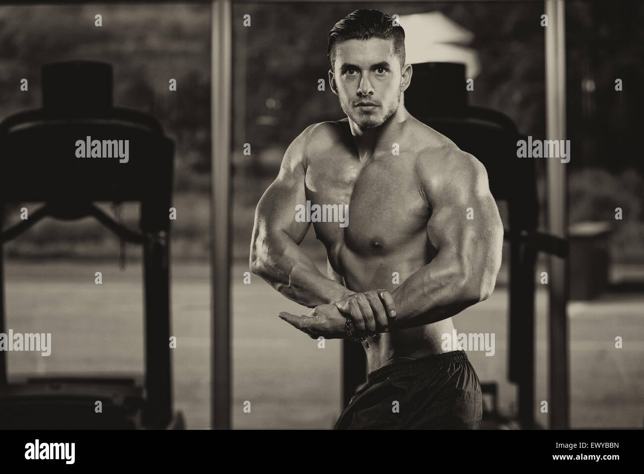 Serious Man Bodybuilder Standing In The Gym And Flexing Muscles Stock ...