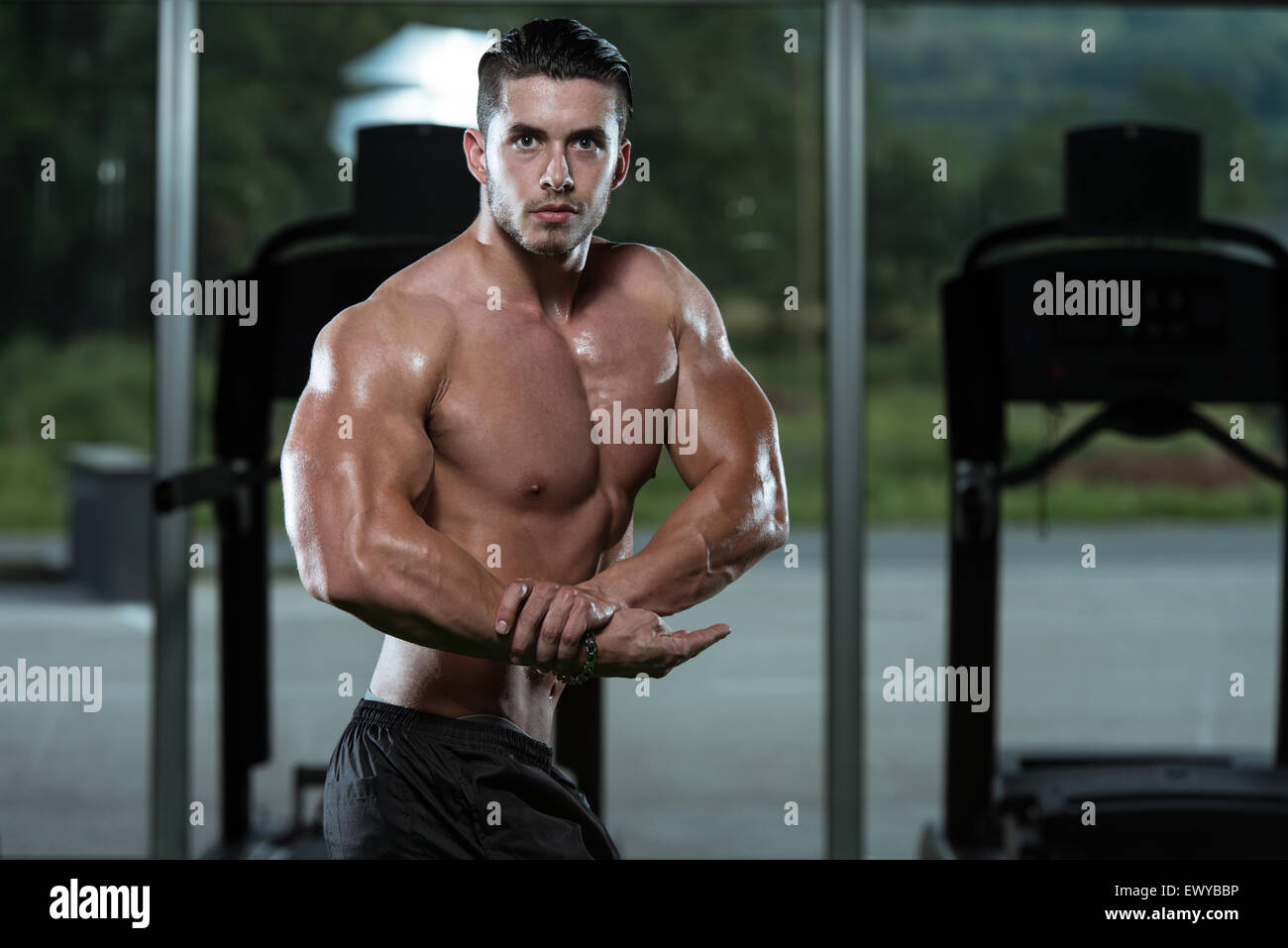 Serious Man Bodybuilder Standing In The Gym And Flexing Muscles Stock ...