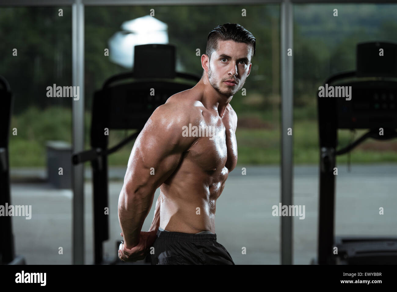 Serious Man Bodybuilder Standing In The Gym And Flexing Muscles Stock ...