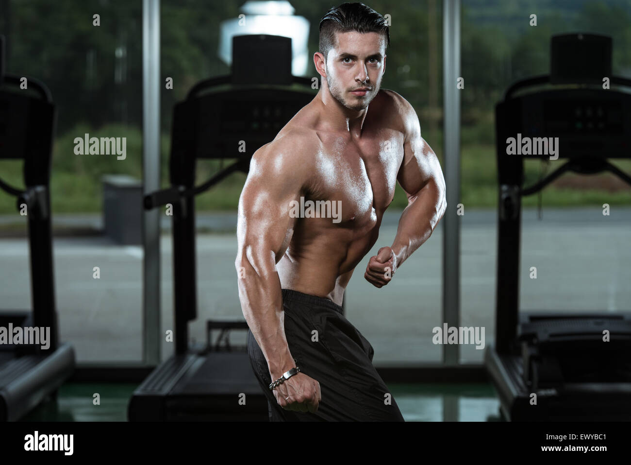 Serious Man Bodybuilder Standing In The Gym And Flexing Muscles Stock ...