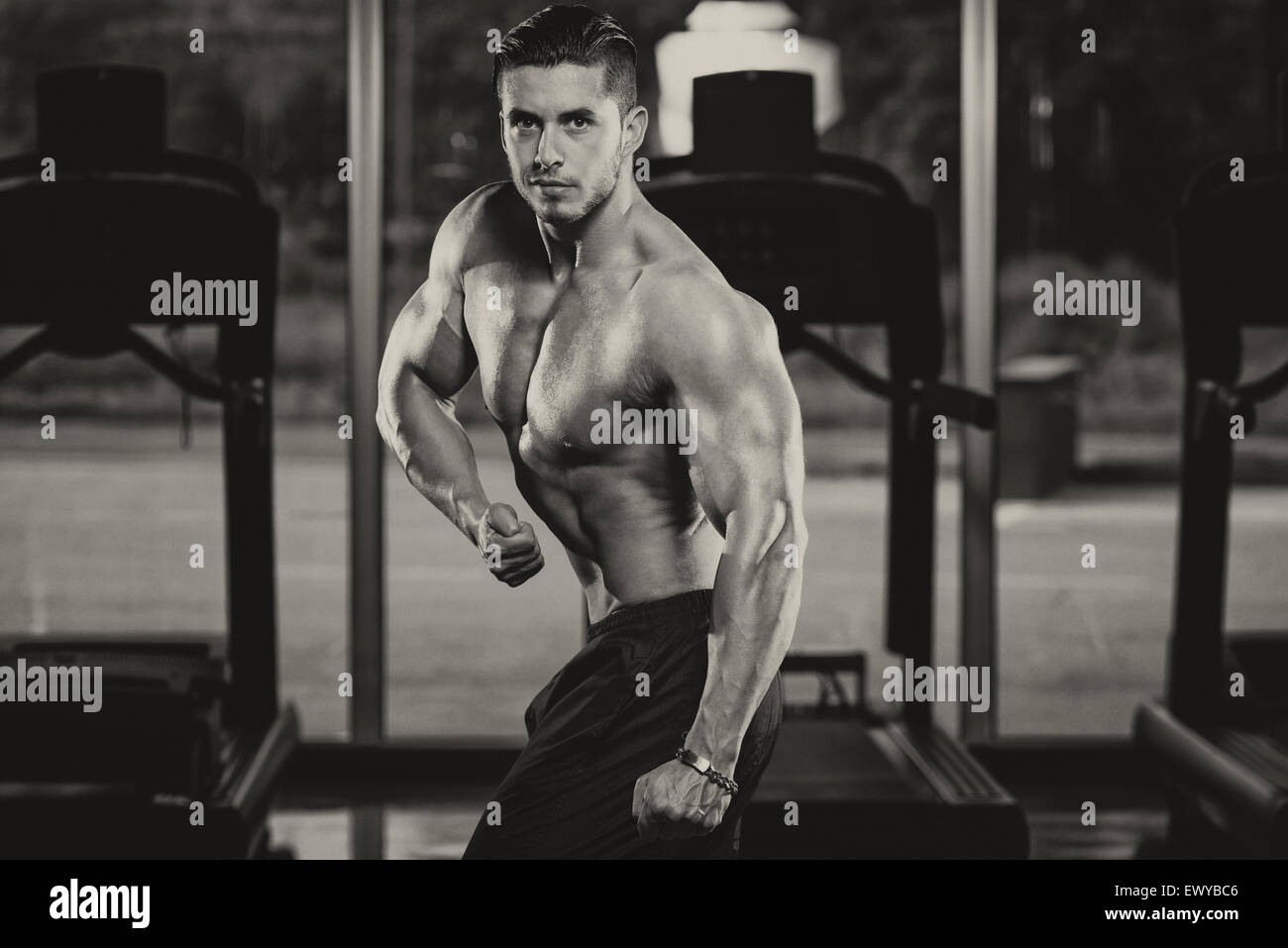 Serious Man Bodybuilder Standing In The Gym And Flexing Muscles Stock ...