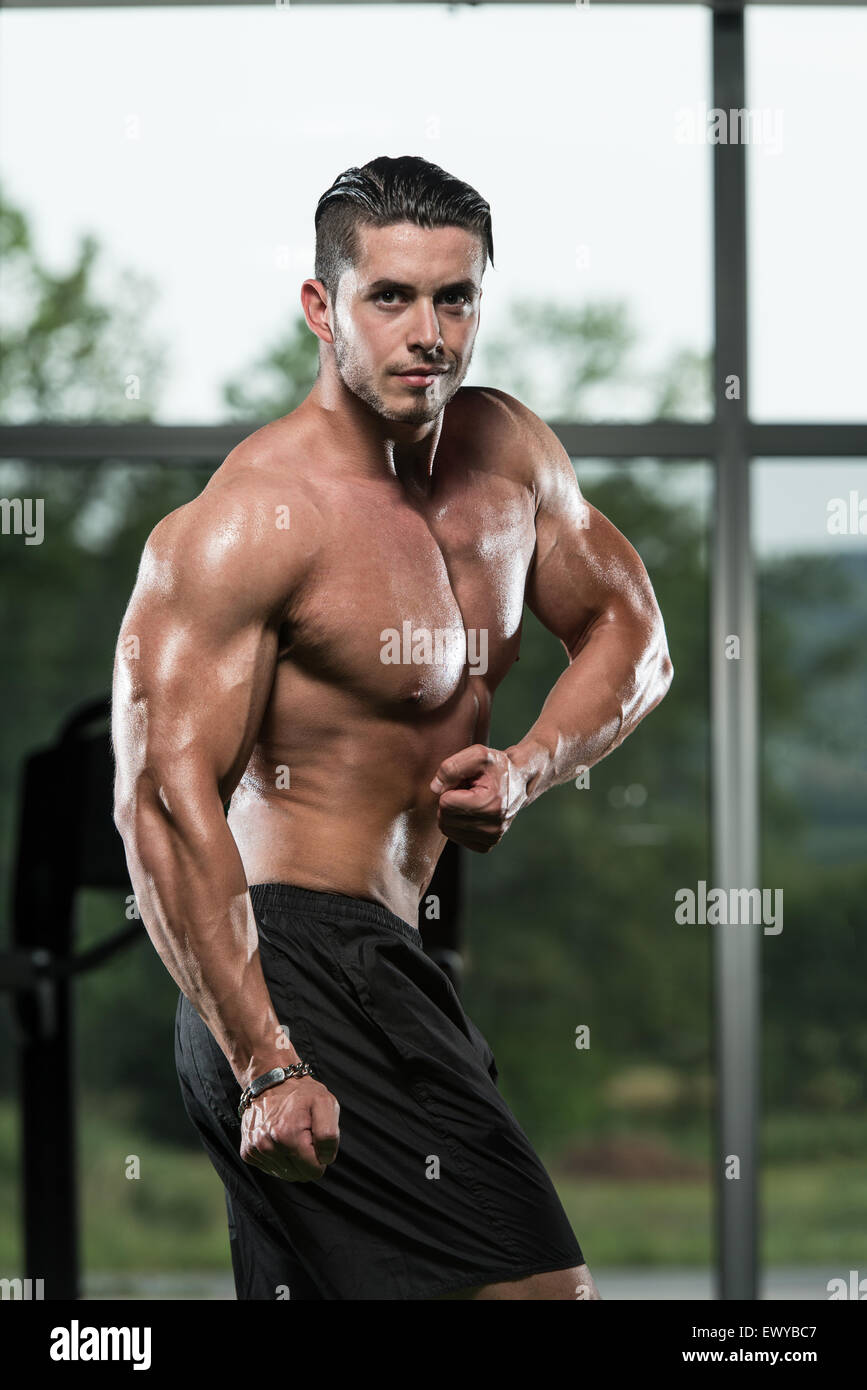 Serious Man Bodybuilder Standing In The Gym And Flexing Muscles Stock ...