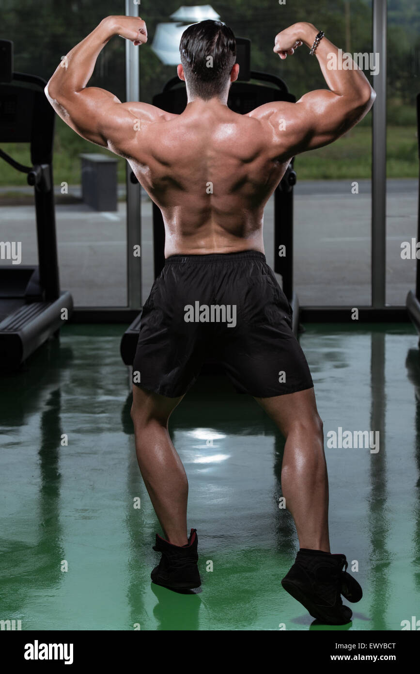 Serious Man Bodybuilder Standing In The Gym And Flexing Muscles Stock ...