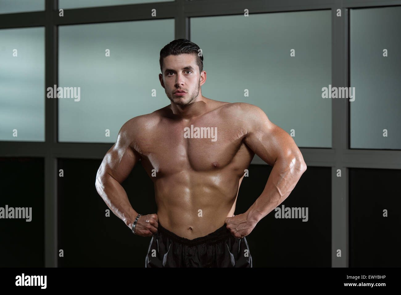Serious Man Bodybuilder Standing In The Gym And Flexing Muscles Stock ...