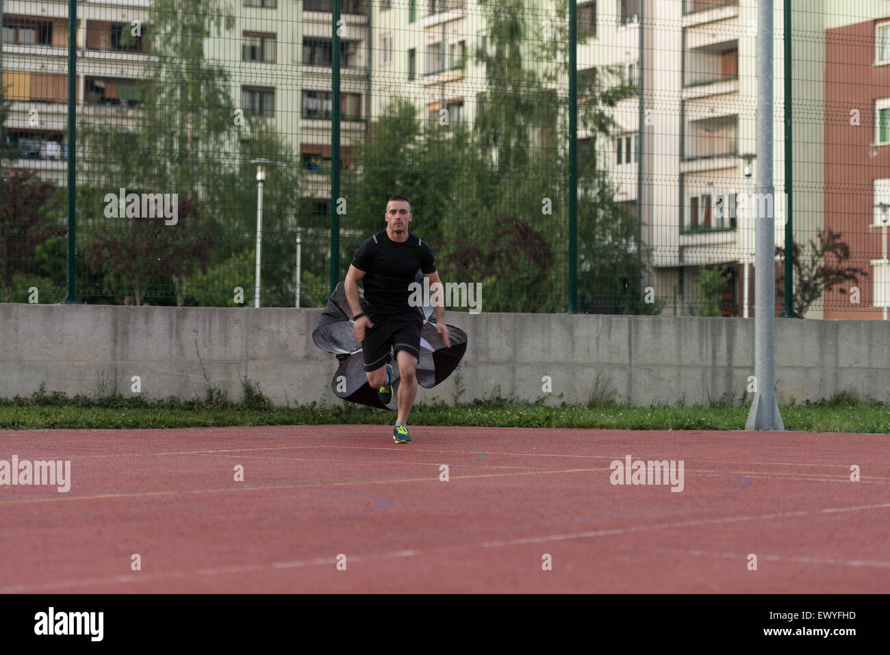 Young Man Running With Parachute On Sports Field Stock Photo - Alamy