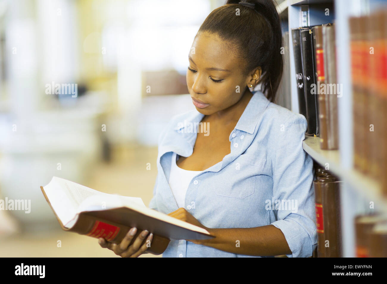 young female African university student reading a book in library Stock ...