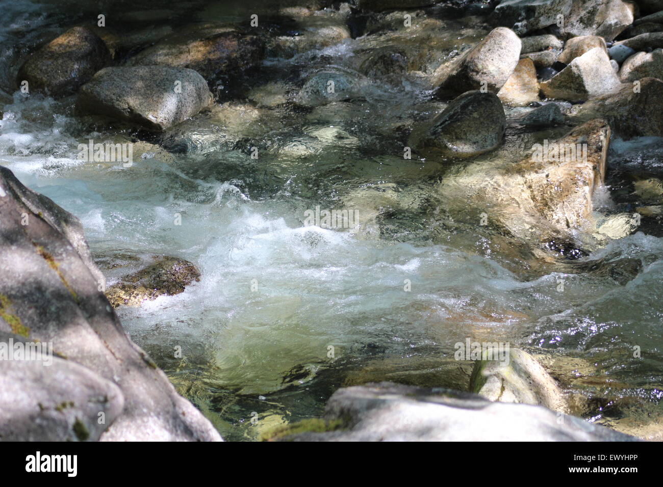 lear water stream running over submerged rocks ideal background or wall ...