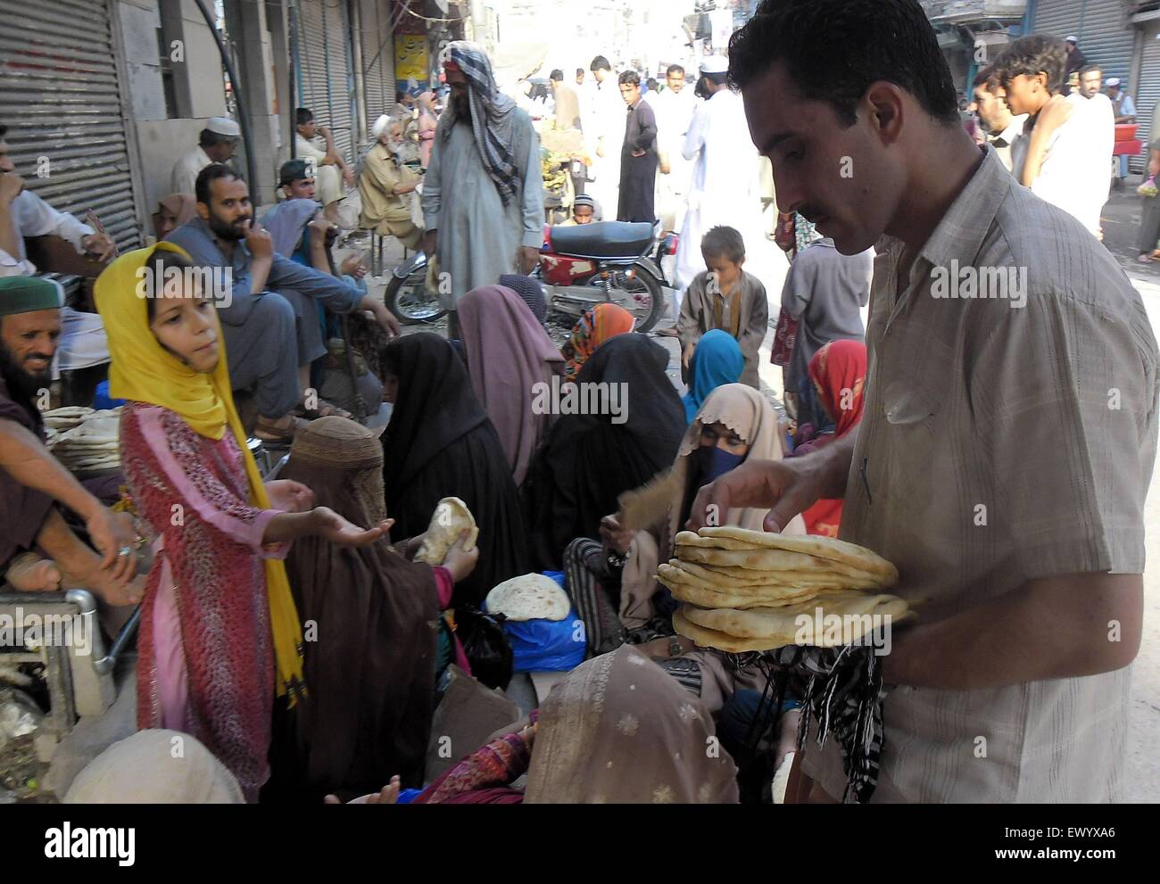 Peshawar. 2nd July, 2015. A man distributes donated food to homeless ...