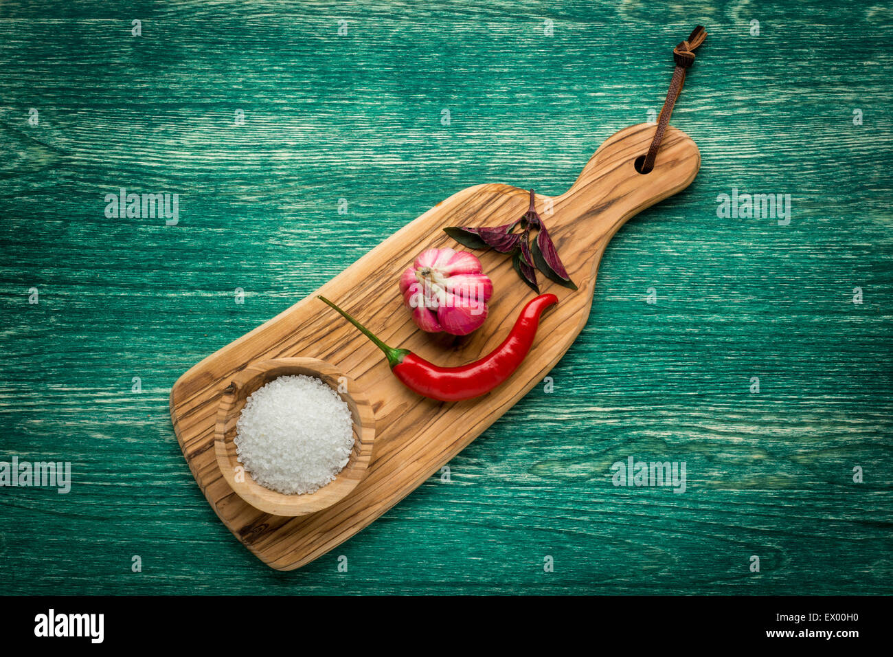 Red chili peppers, garlic, basil and salt over a wooden background ...