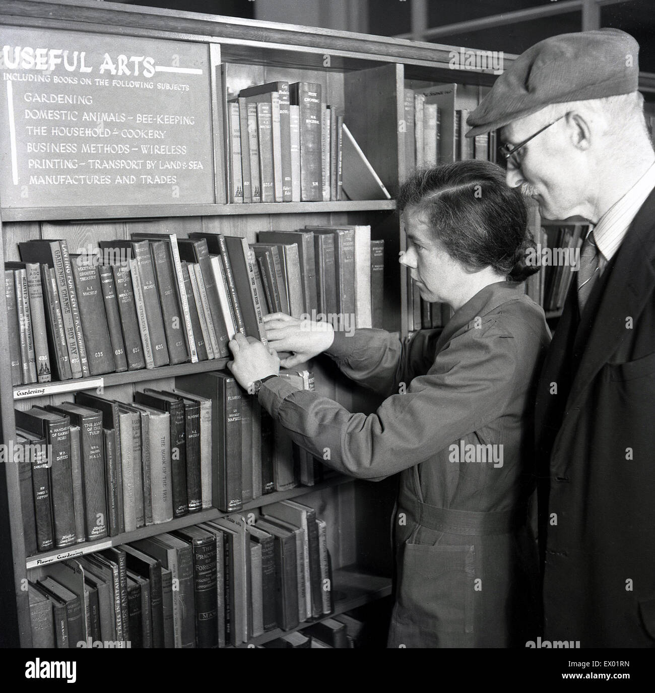 Historical, 1950s, young female librarian helping an elderly man in a ...