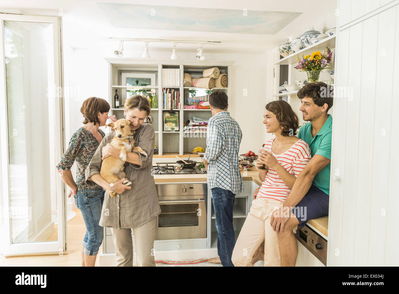 Five adult friends and dog gathering in kitchen Stock Photo - Alamy