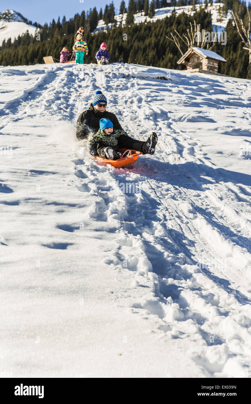 Father and son riding sled down snow-covered slope, Achenkirch, Tirol ...