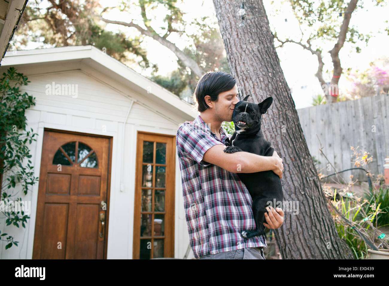Young man kissing dog outside front door Stock Photo - Alamy