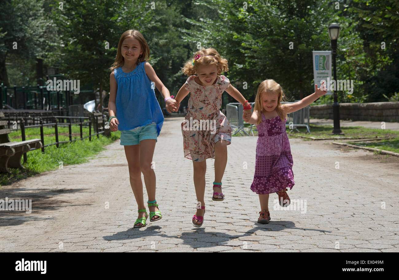 Girls having fun in a park running skipping along a footpath. New York ...