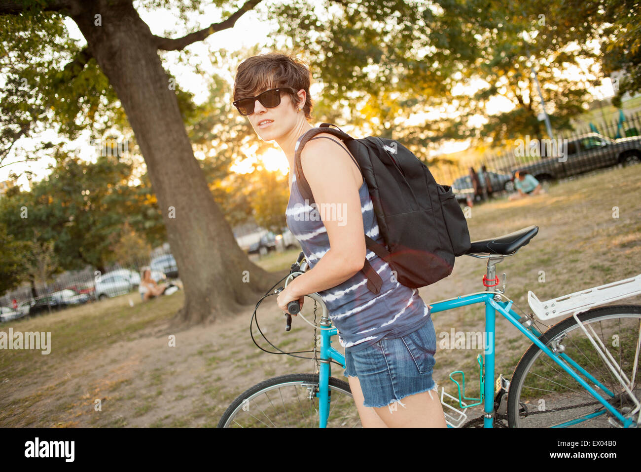 Female cyclist pushing bicycle through park Stock Photo - Alamy