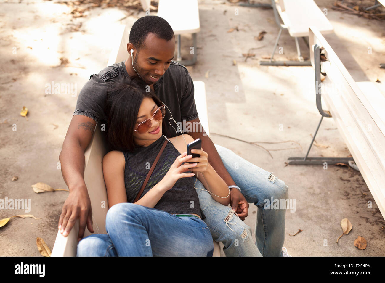 Young couple sitting together, sharing earphones Stock Photo - Alamy