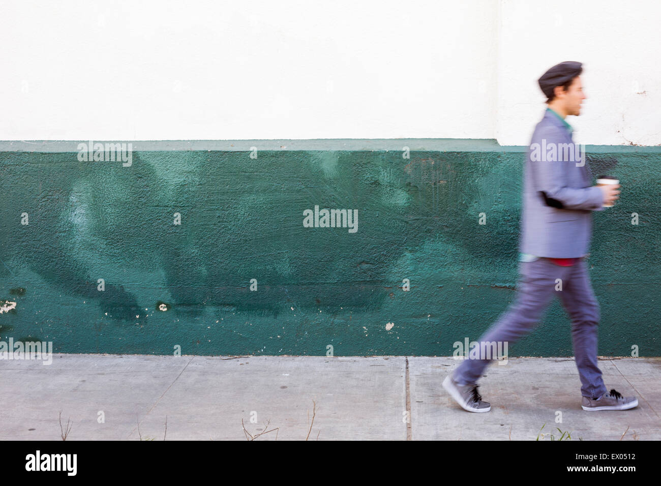 Young man walking past wall Stock Photo - Alamy