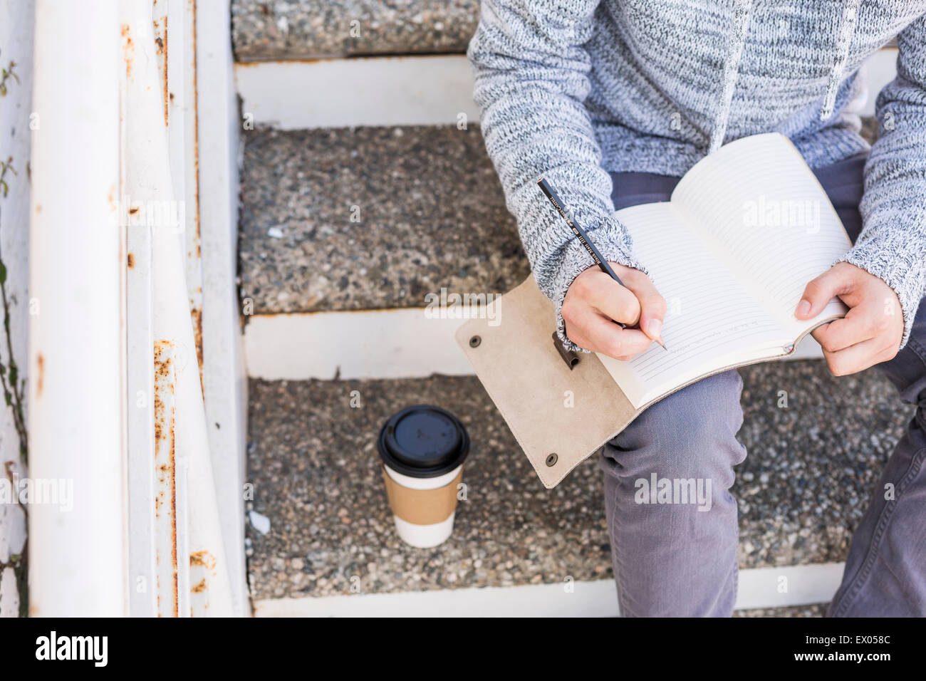 Man sitting on steps writing in notebook Stock Photo - Alamy