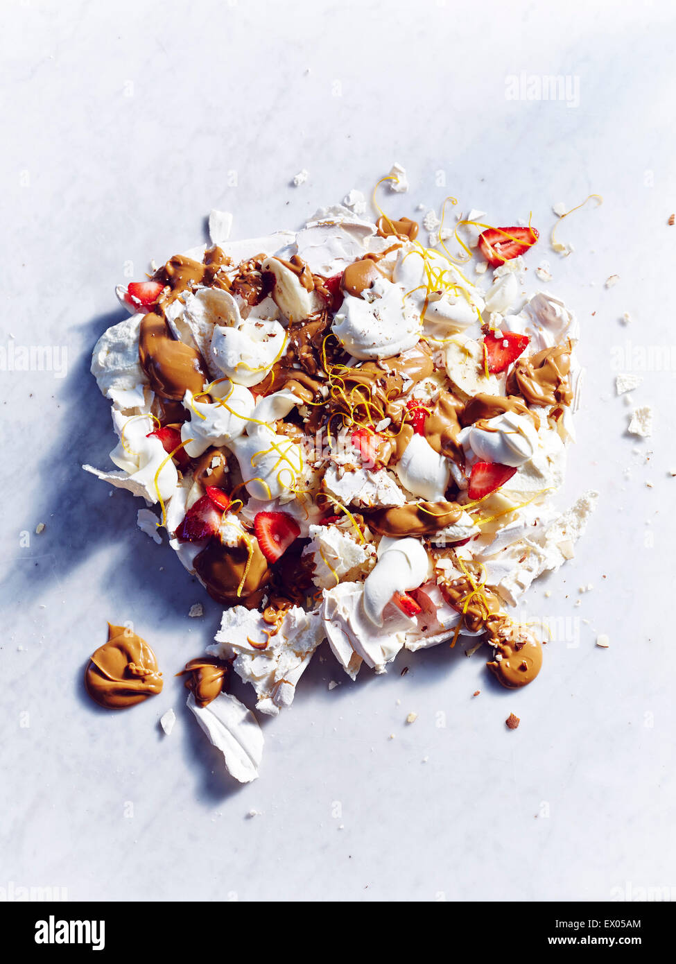 Table of smashed pavlova with strawberries, cream, dulce de leche and ...