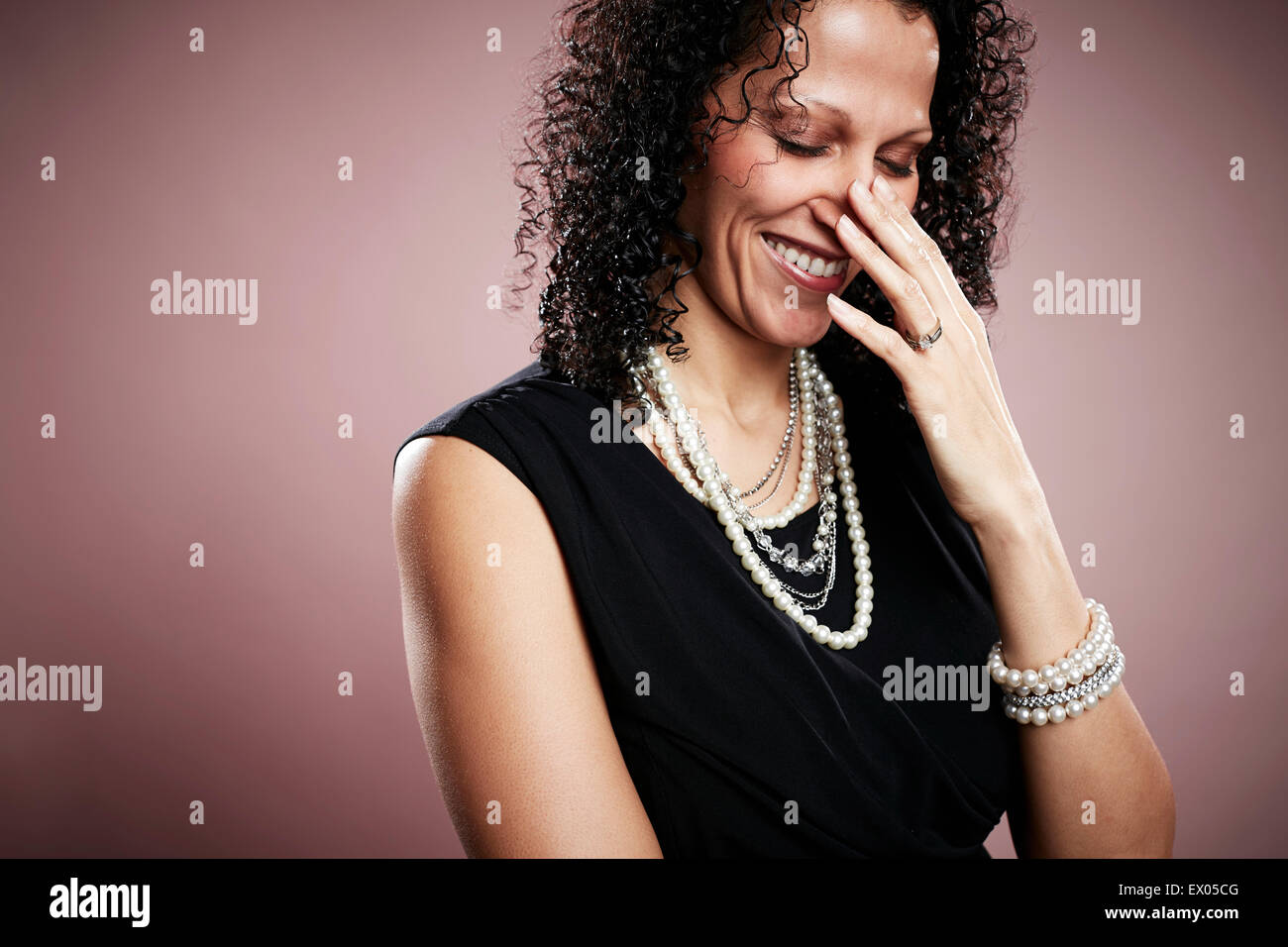 Studio portrait of mature woman with hand on face giggling Stock Photo ...