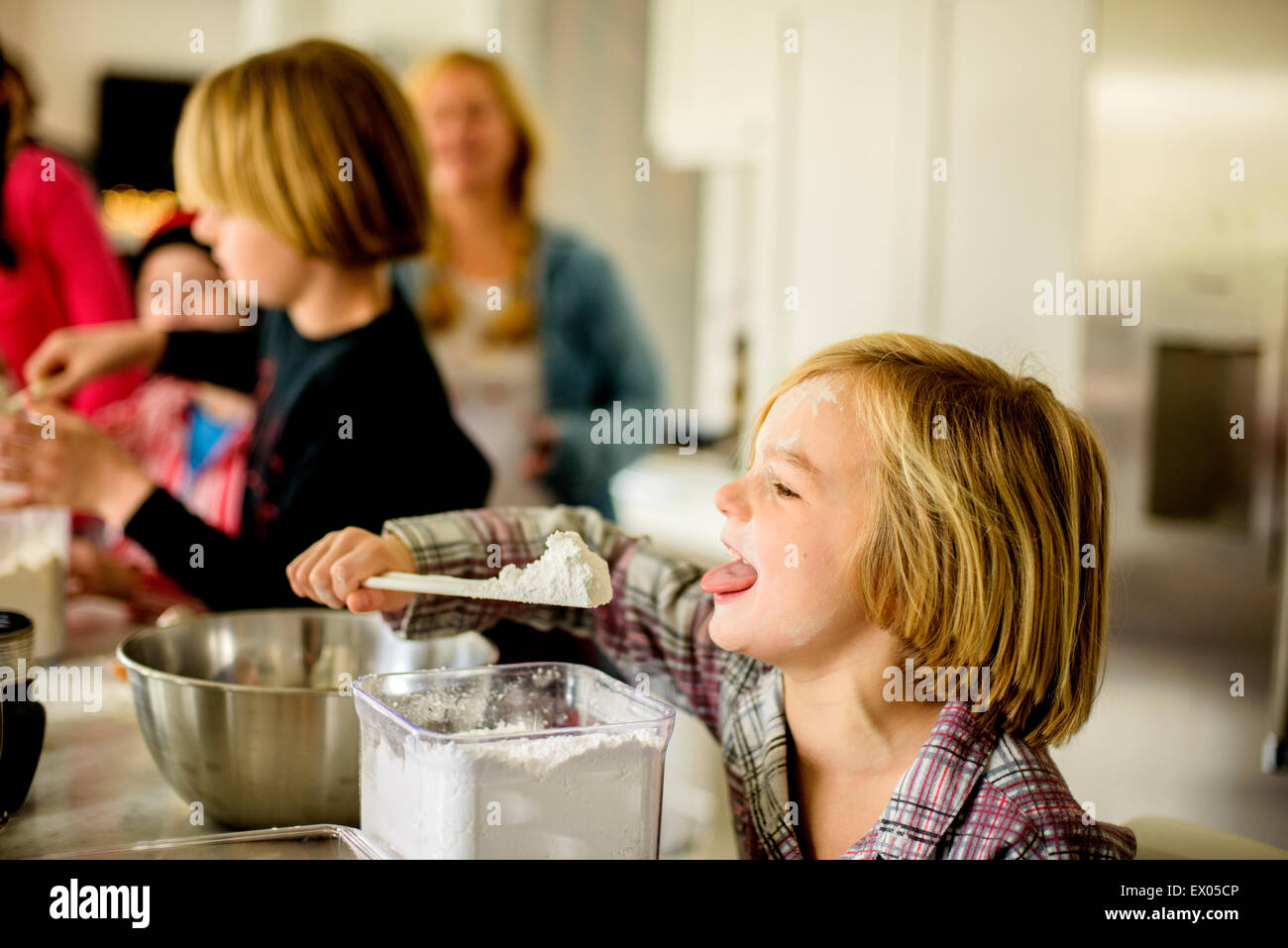 Boy eating icing sugar from spatula in kitchen Stock Photo - Alamy