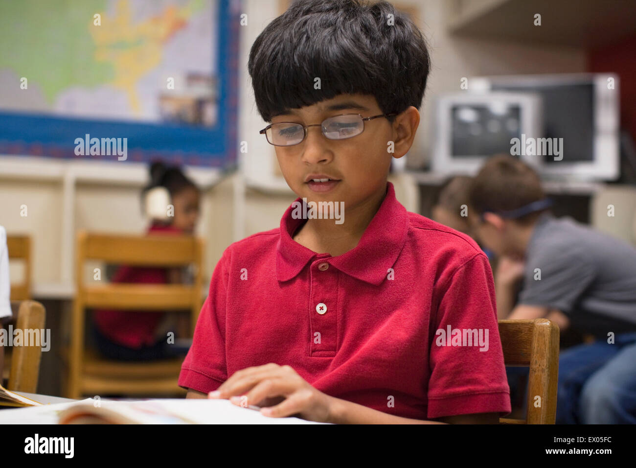 Boy reading book in classroom Stock Photo - Alamy